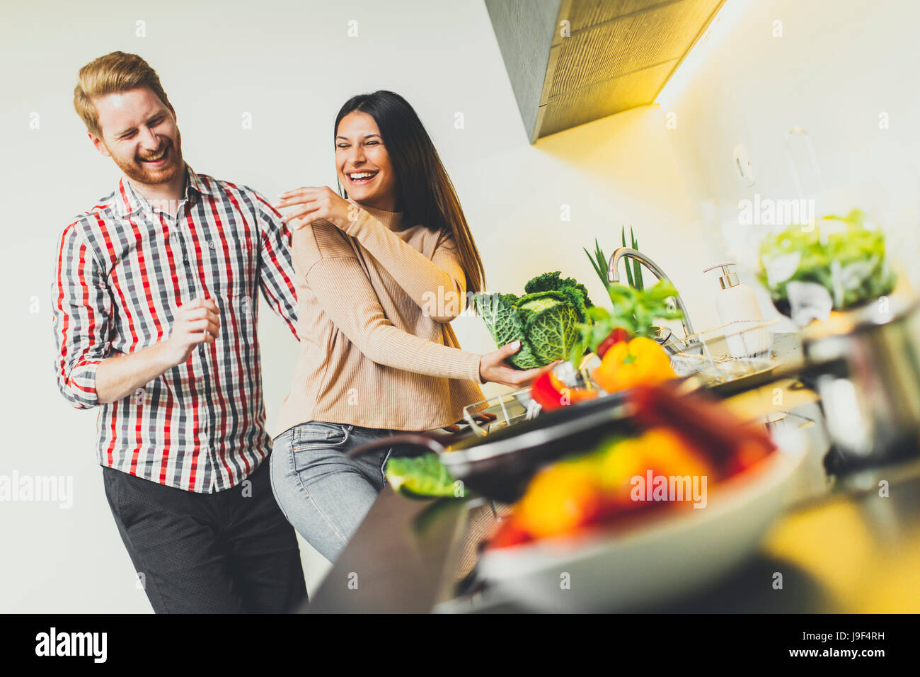 Happy young couple have fun in modern kitchen indoor while preparing ...