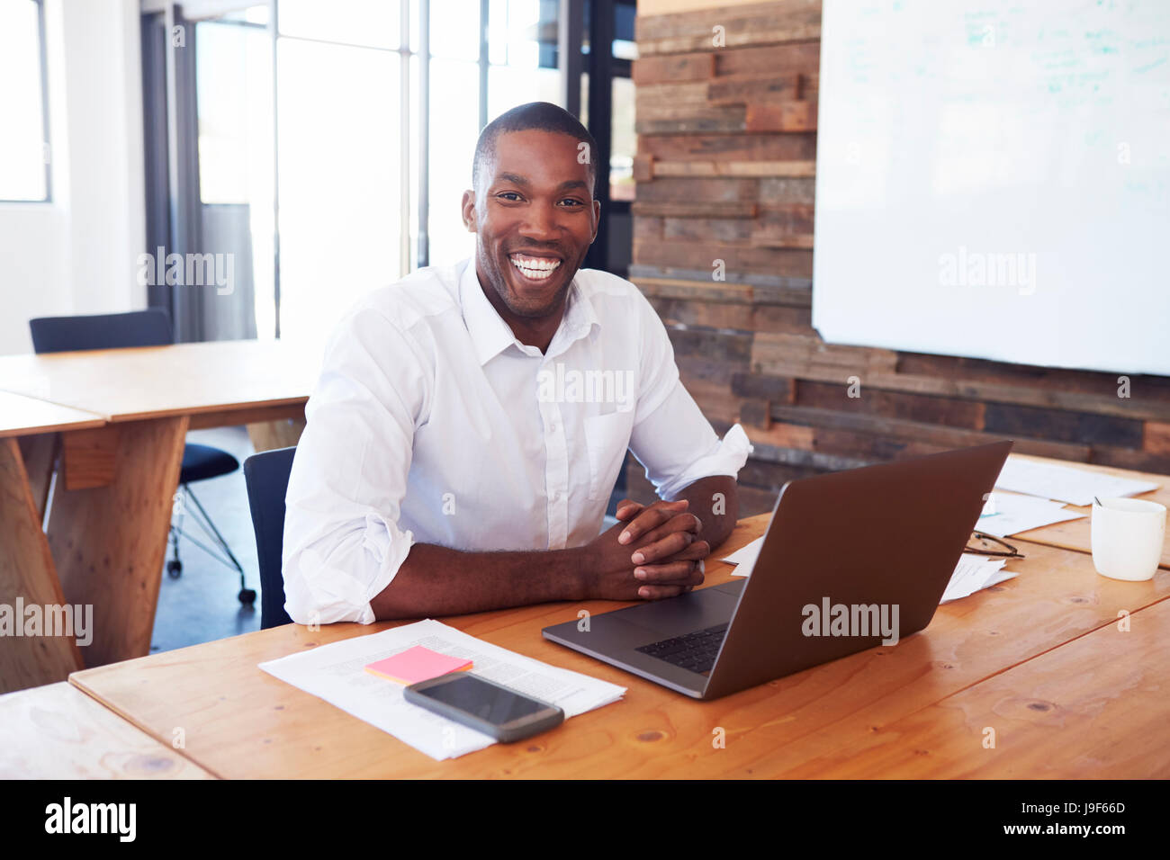 Young black man at desk with laptop computer looks to camera Stock ...