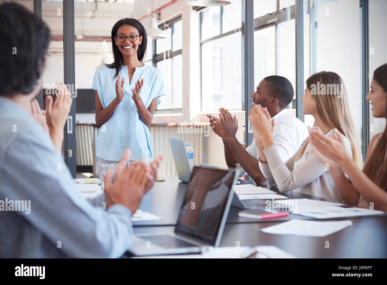 Young black woman stands clapping with colleagues at meeting Stock ...