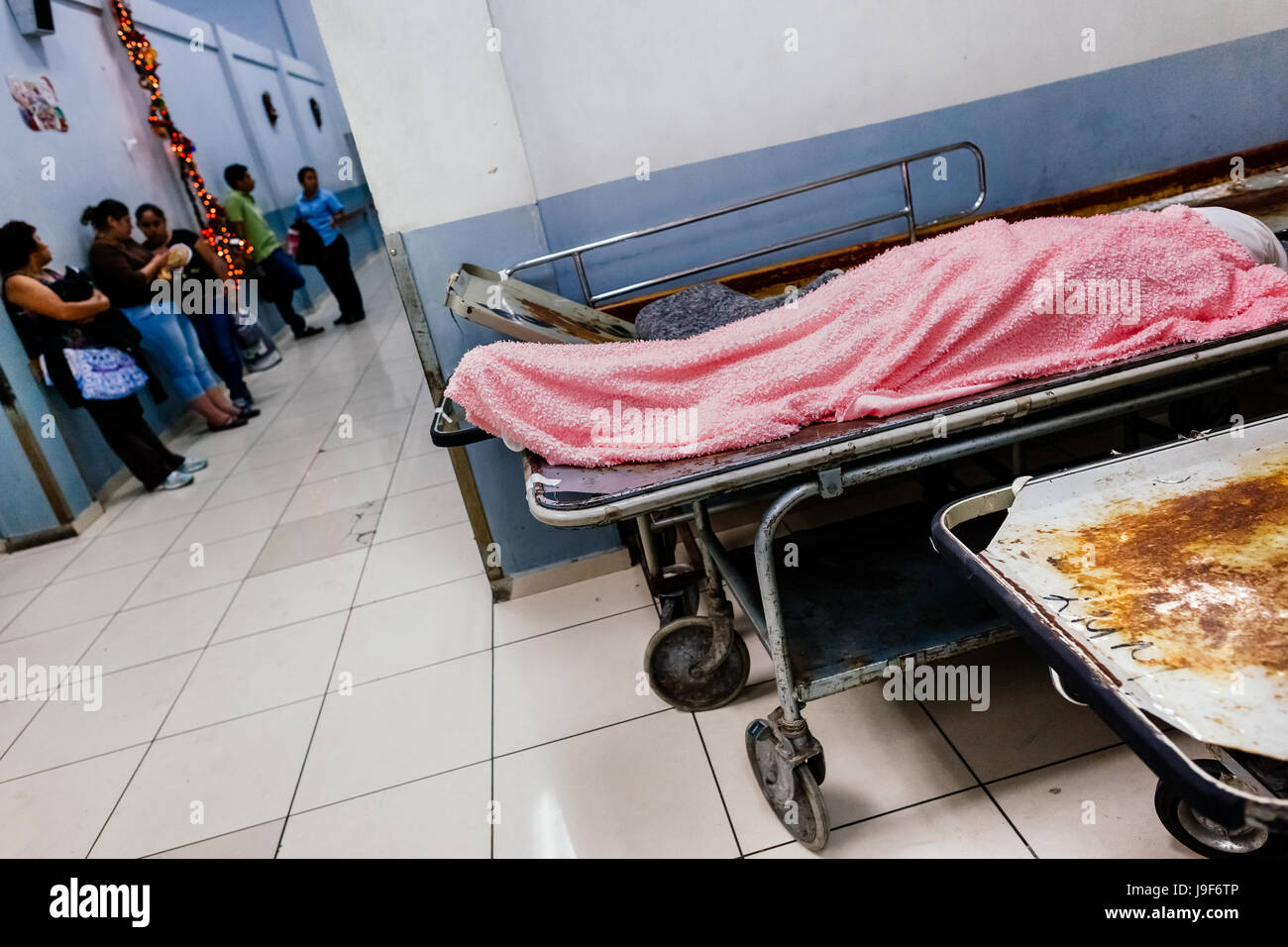 A dead body of a deceased patient, covered by a bath towel, lies on the ...