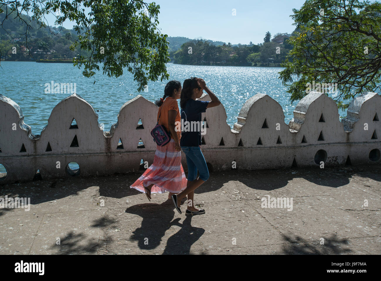 Two friends walk along the promenade next to the lake in Kandy, Sri ...