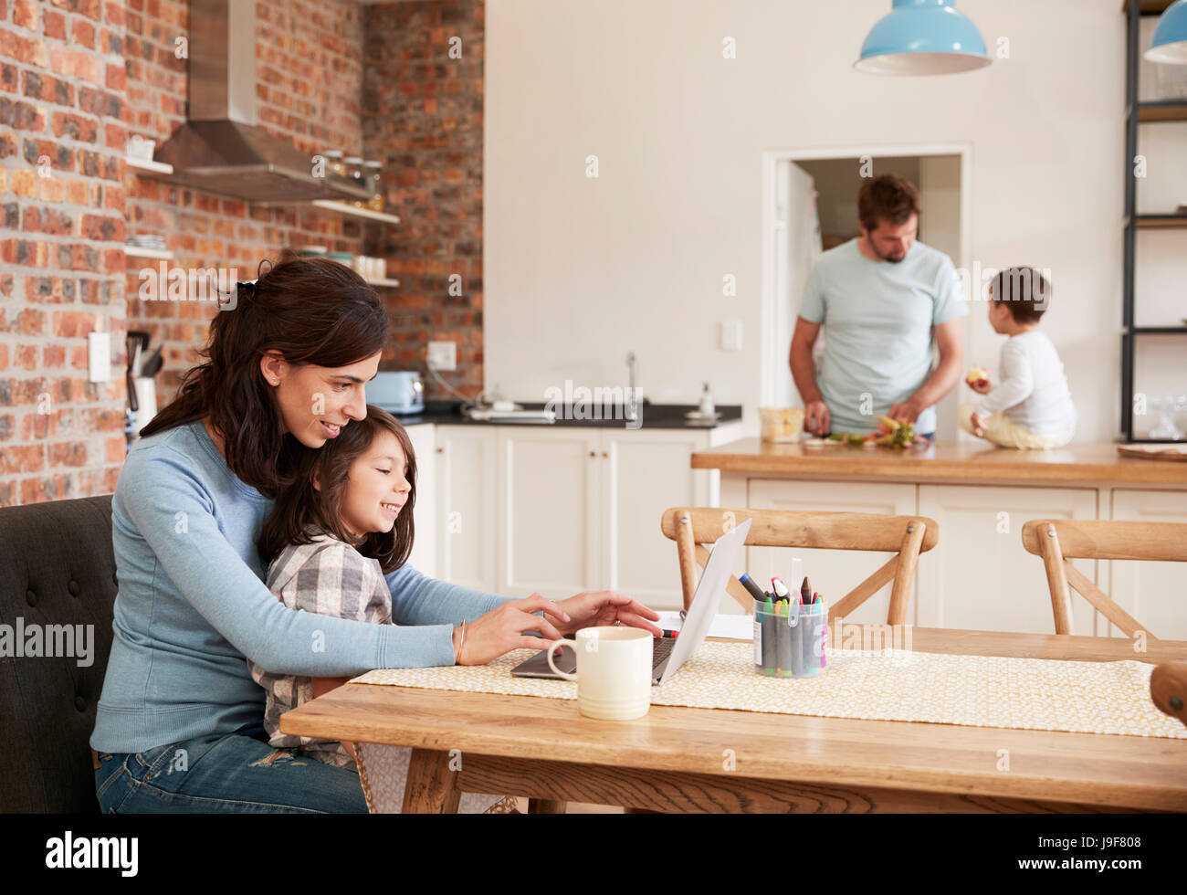 Busy Family Home With Mother Working As Father Prepares Meal Stock ...