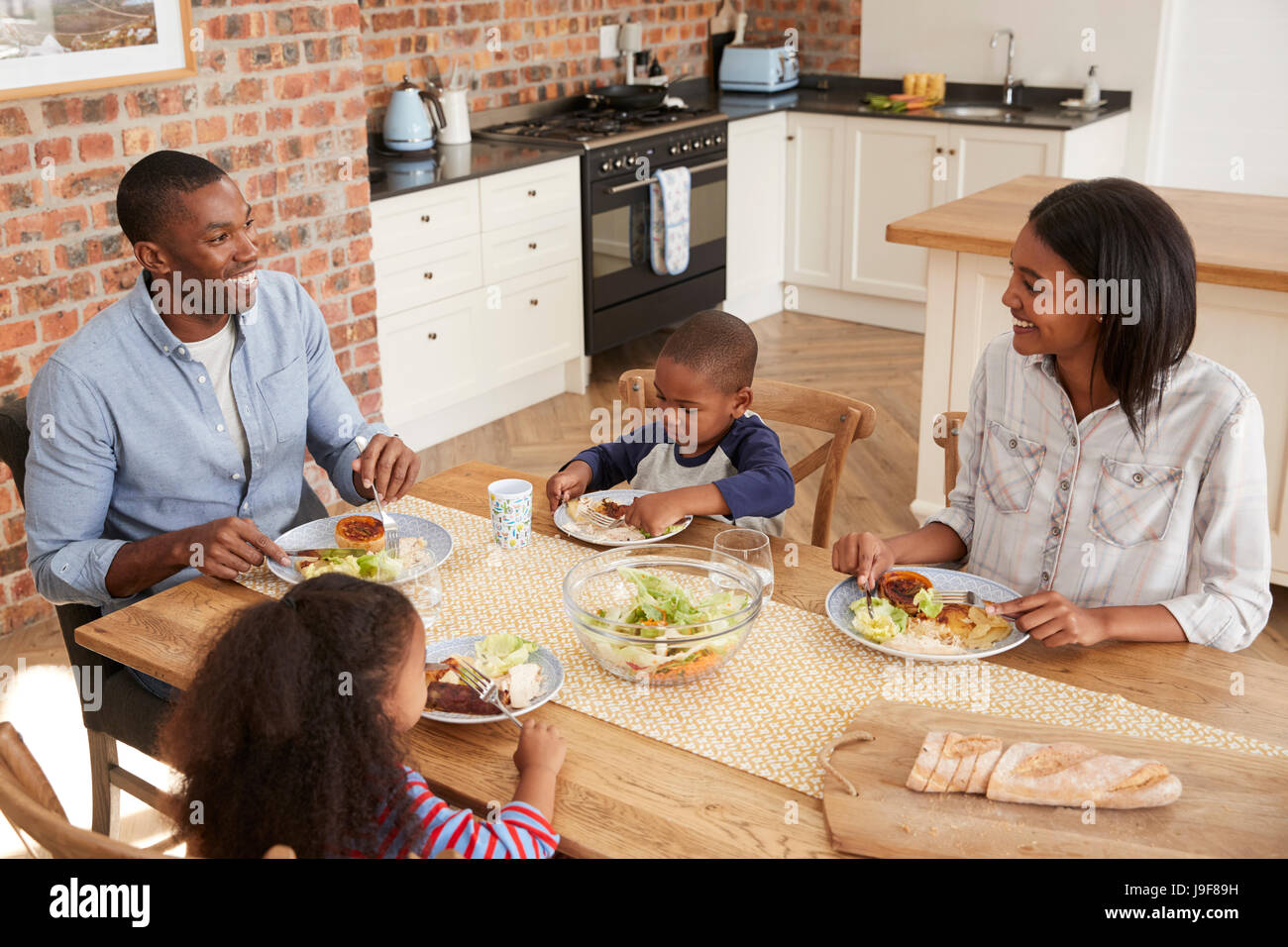 Family Eating Meal In Open Plan Kitchen Together Stock Photo - Alamy