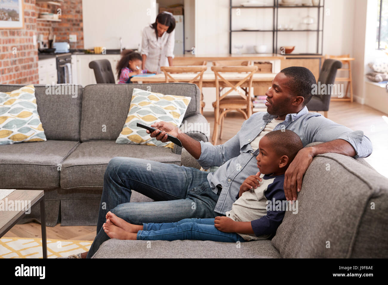 Father And Son Sit On Sofa In Lounge Watching Television Stock Photo ...