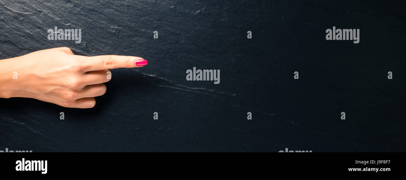 Young woman hand pointing on dark background Stock Photo - Alamy
