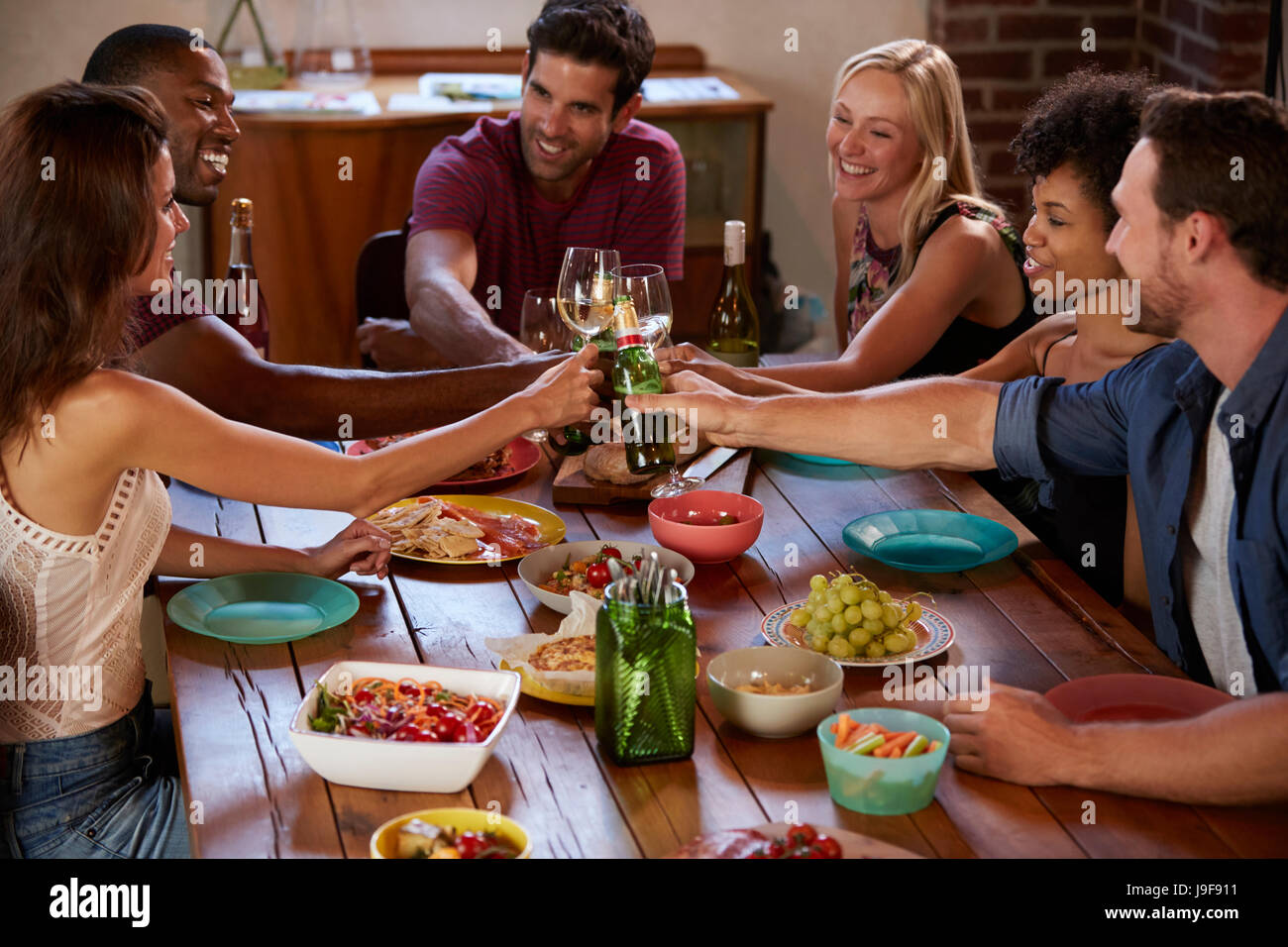Happy friends talking raising toast hi-res stock photography and images ...