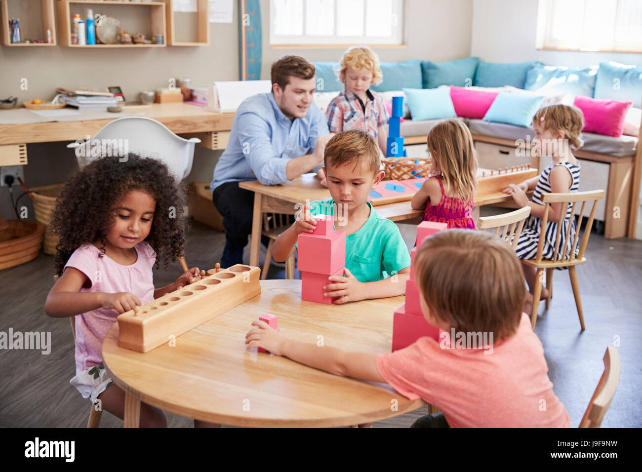 Teacher And Pupils Working At Tables In Montessori School Stock Photo ...