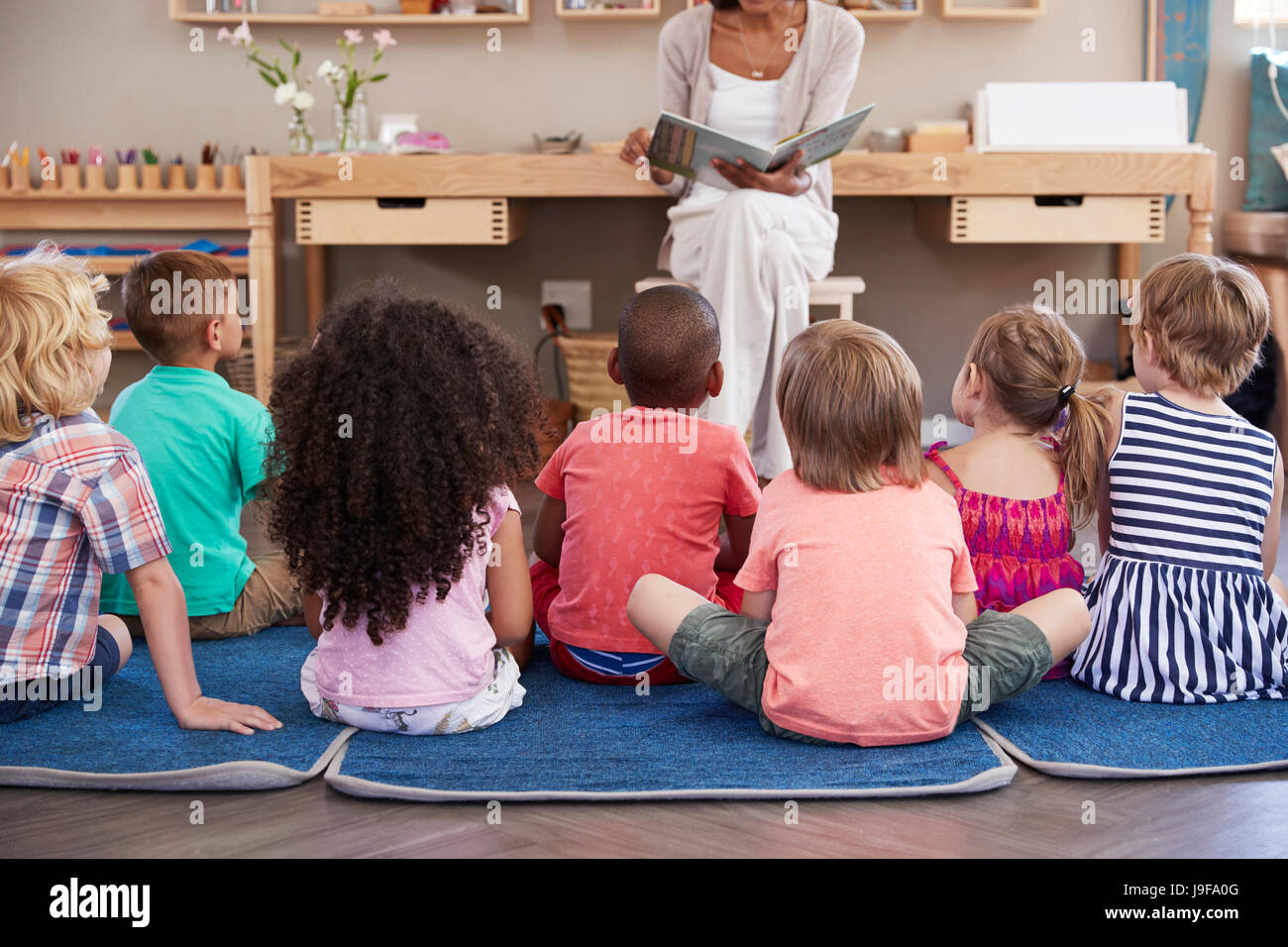 Teacher At Montessori School Reading To Children At Story Time Stock ...