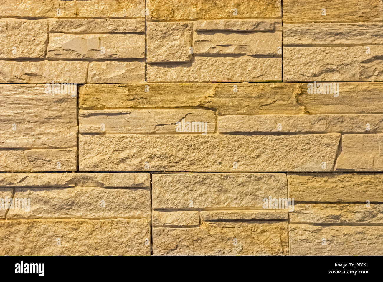 The wall is lined with beige rectangular tiles with a voluminous, rough ...