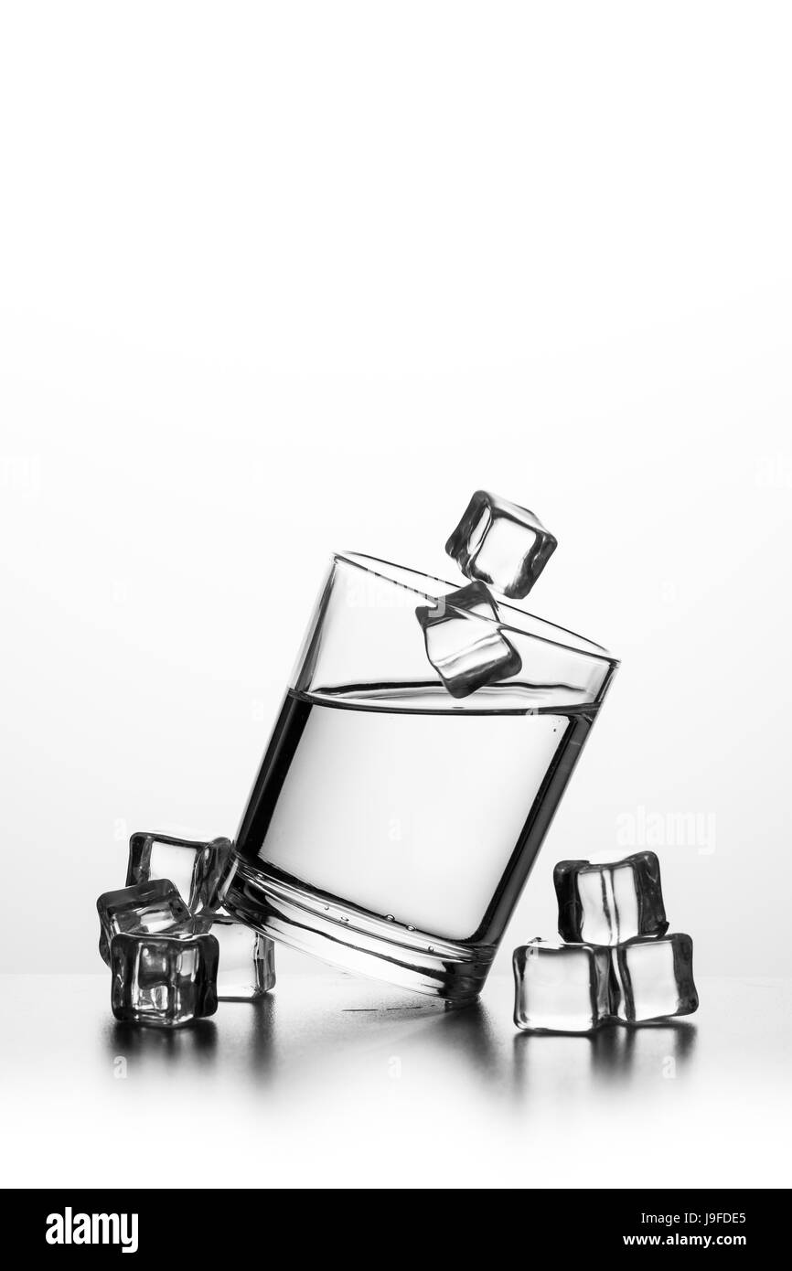 Cube of ice thrown into a glass with transparent liquid Stock Photo - Alamy