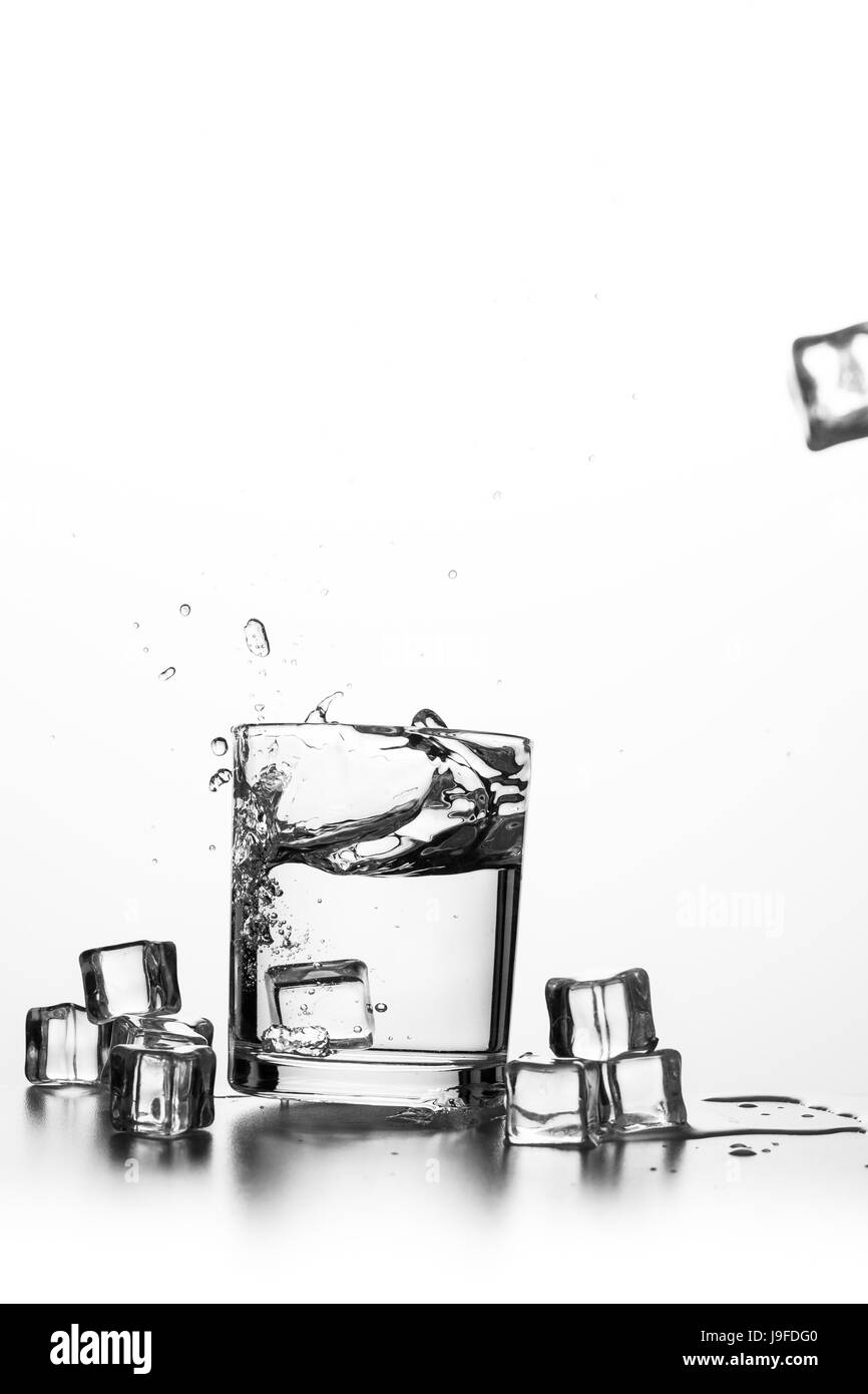 Cube of ice thrown into a glass with transparent liquid Stock Photo - Alamy
