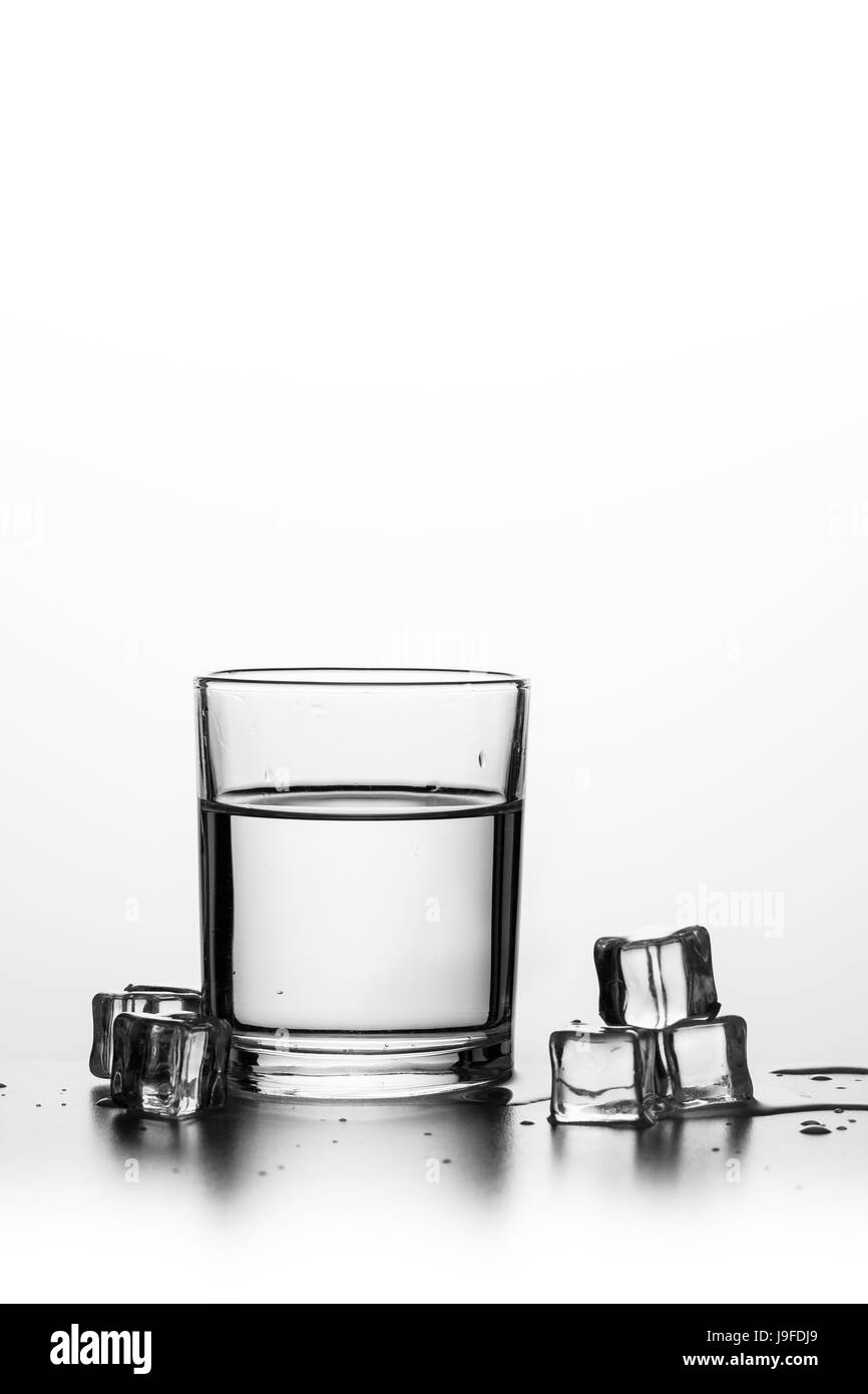 Cube of ice thrown into a glass with transparent liquid Stock Photo - Alamy