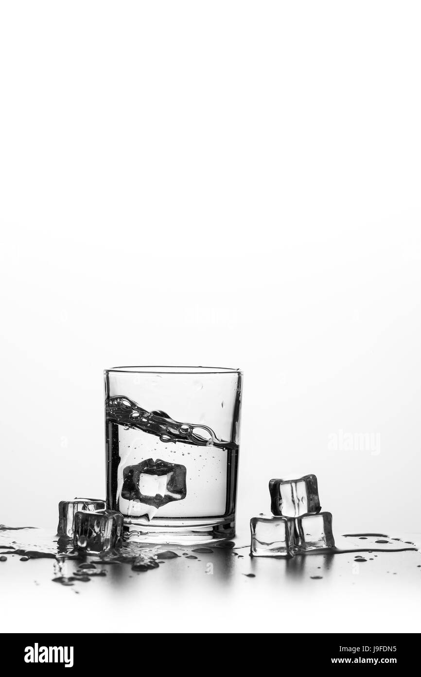 Cube of ice thrown into a glass with transparent liquid Stock Photo - Alamy