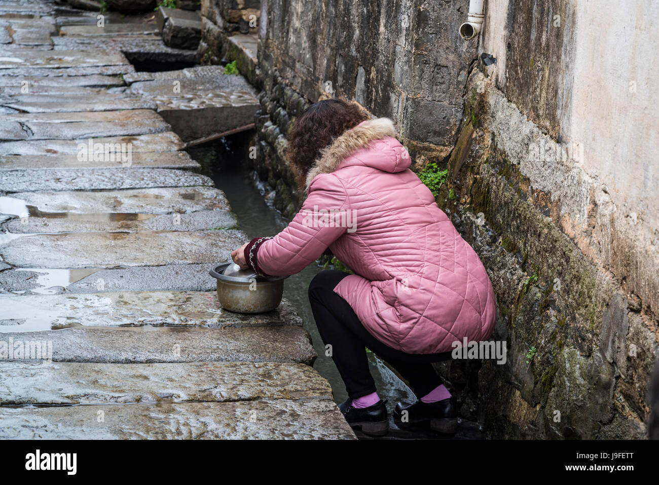 Woman washing saucepan in waterway in the street, Ancient Hongcun ...