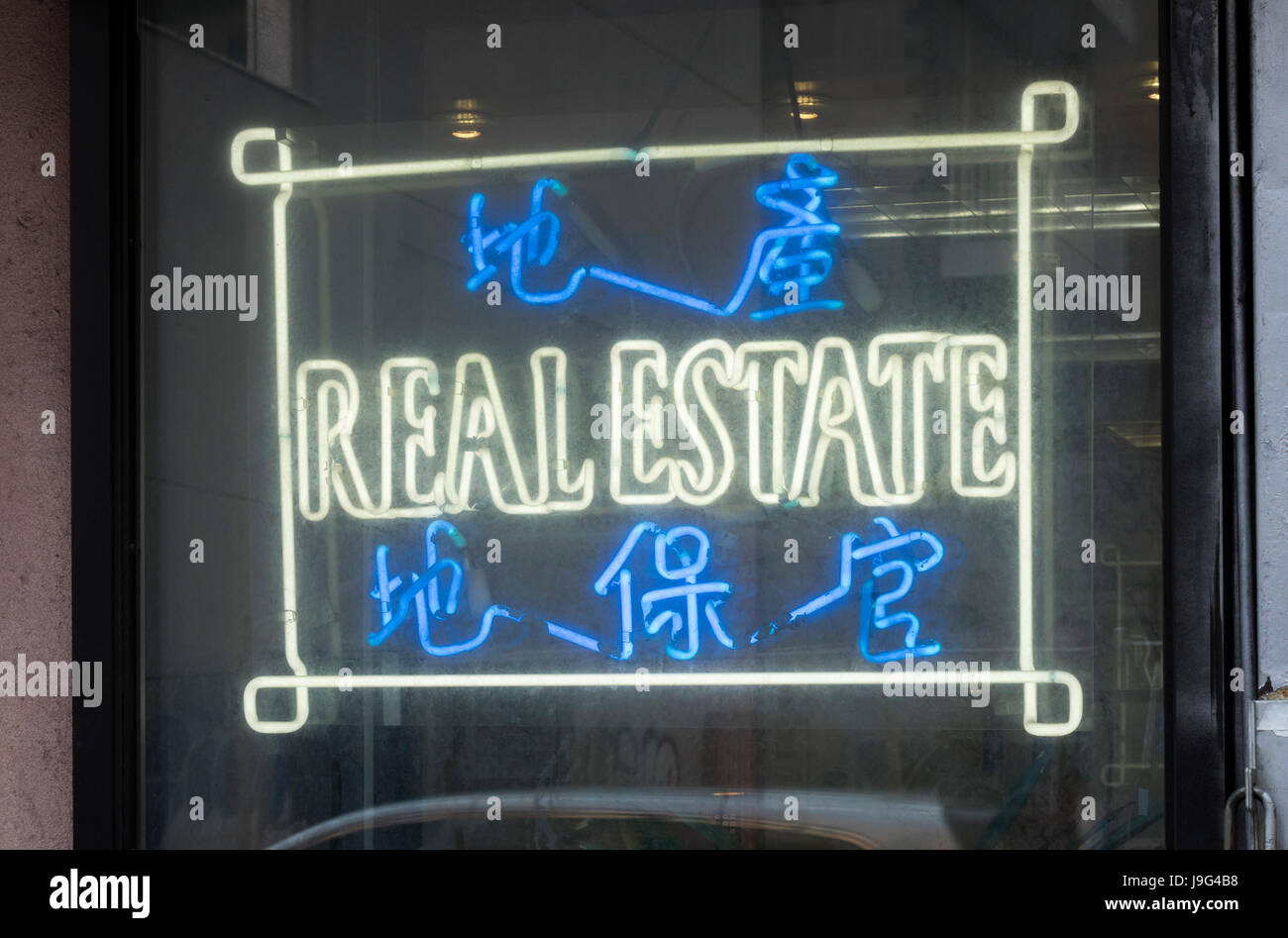 A neon real estate sign in English and Chinese in an office window in ...