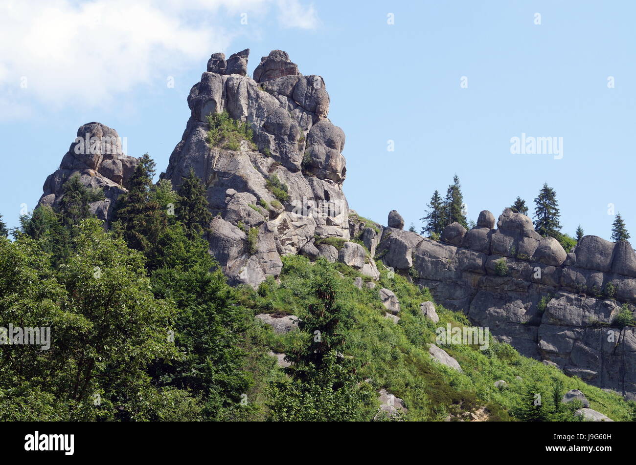 High stone rock in a green forest under a blue sky Stock Photo - Alamy