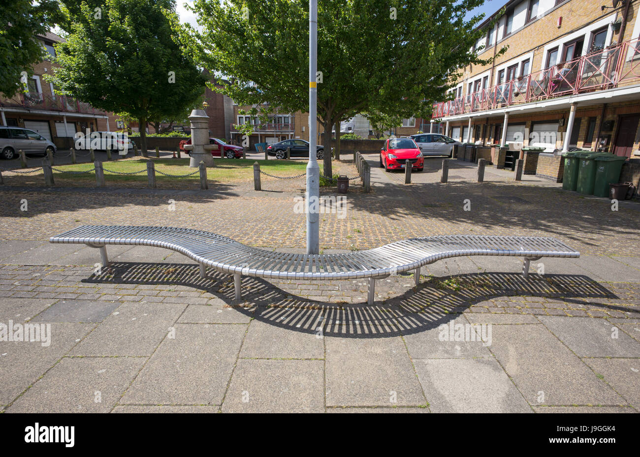 Curved stainless steel bench at base of lamp post near housing ...