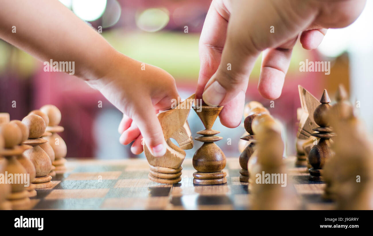 clsoe up chess game move shot with kid and parent hand Stock Photo - Alamy
