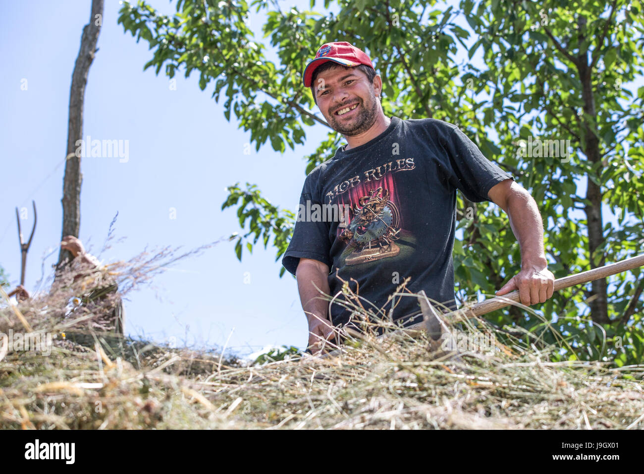 Romanian farmers at work on a cart full of hay. Happy and smiling ...