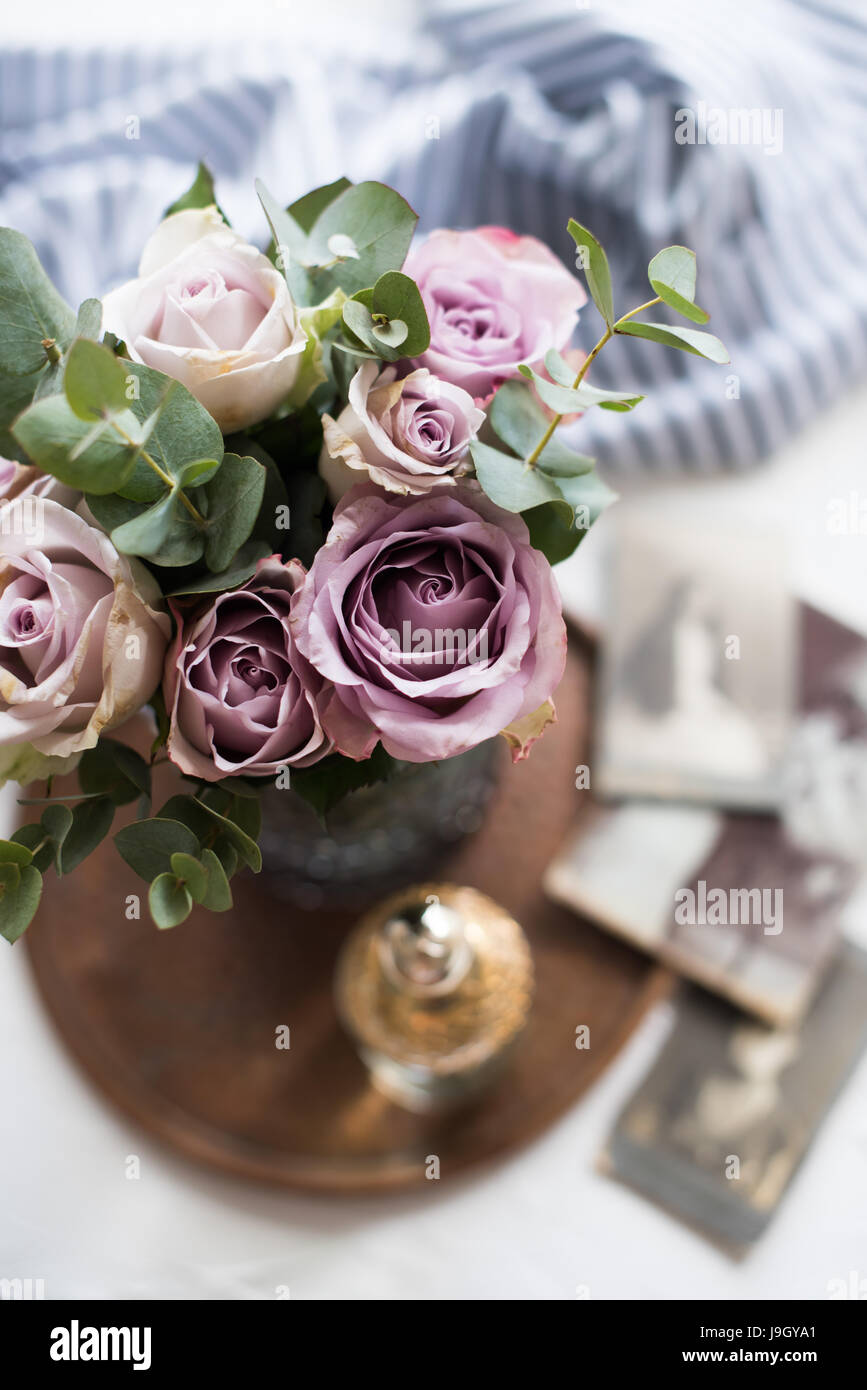 Pastel purple, mauve color fresh summer roses in vase in tray closeup ...