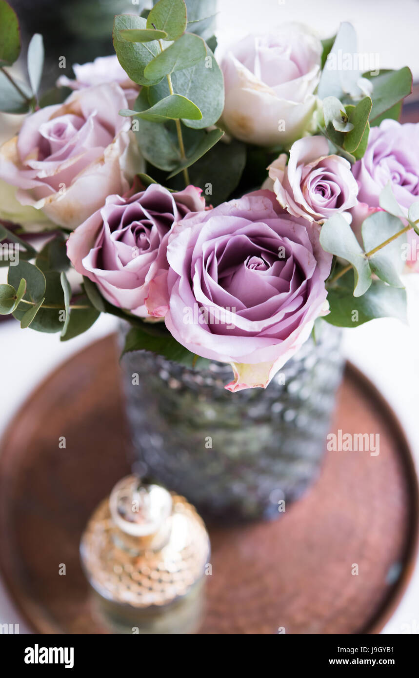 Pastel purple, mauve color fresh summer roses in vase and perfume in ...