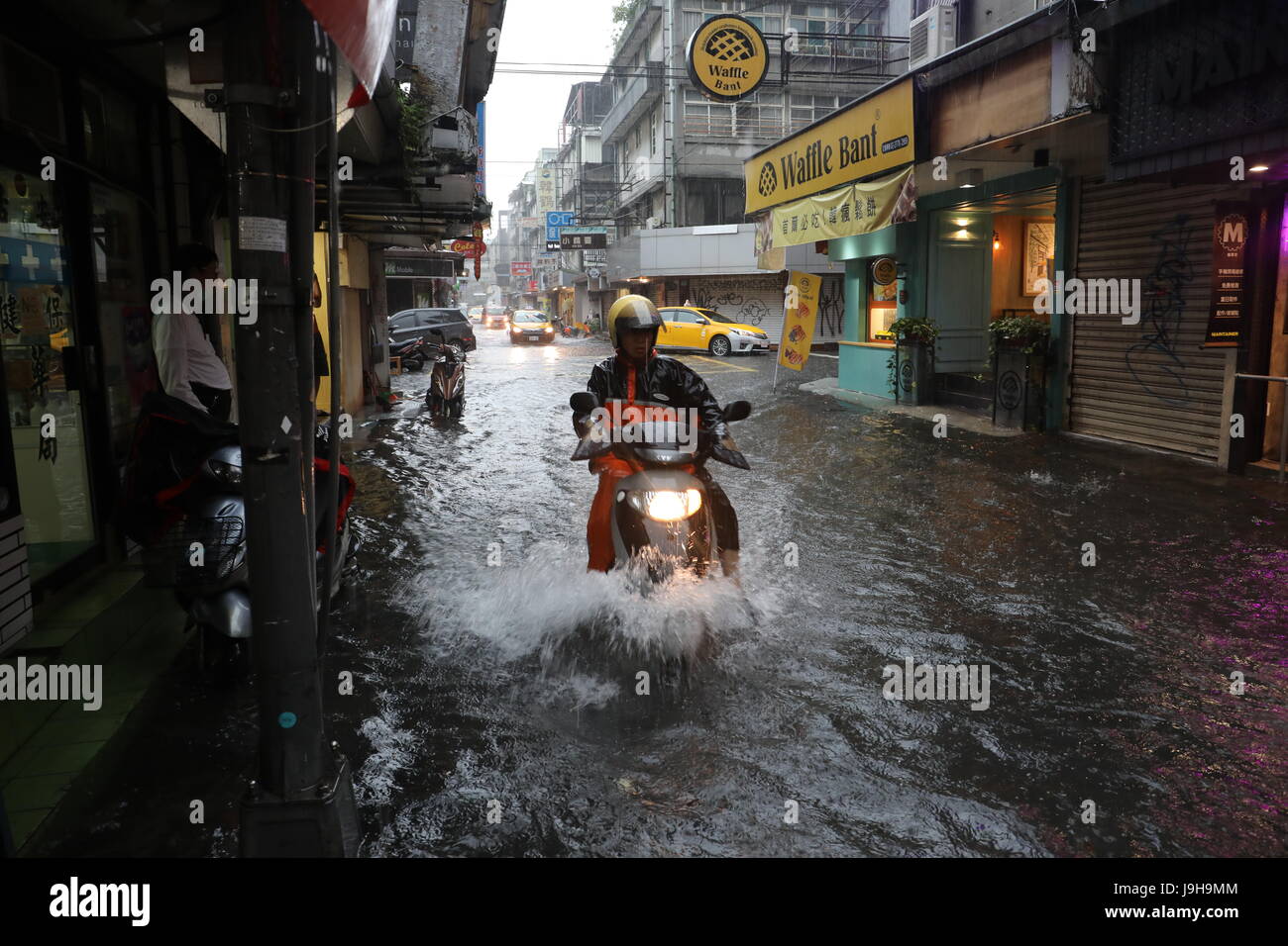 Taipei, Taiwan. 2nd June, 2017. A scooter drives down a flooded back ...