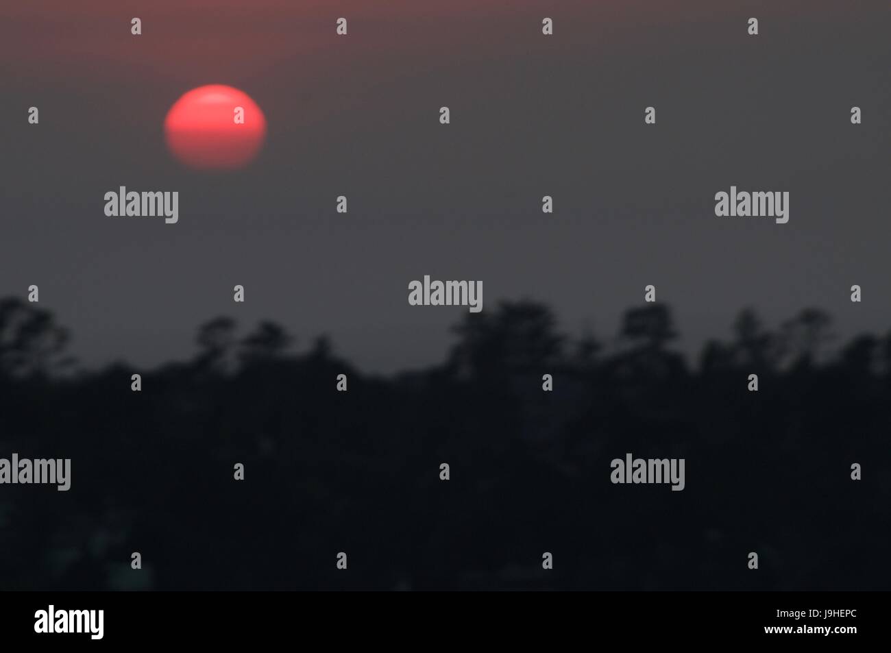 Red sun setting over dark landscape Stock Photo - Alamy
