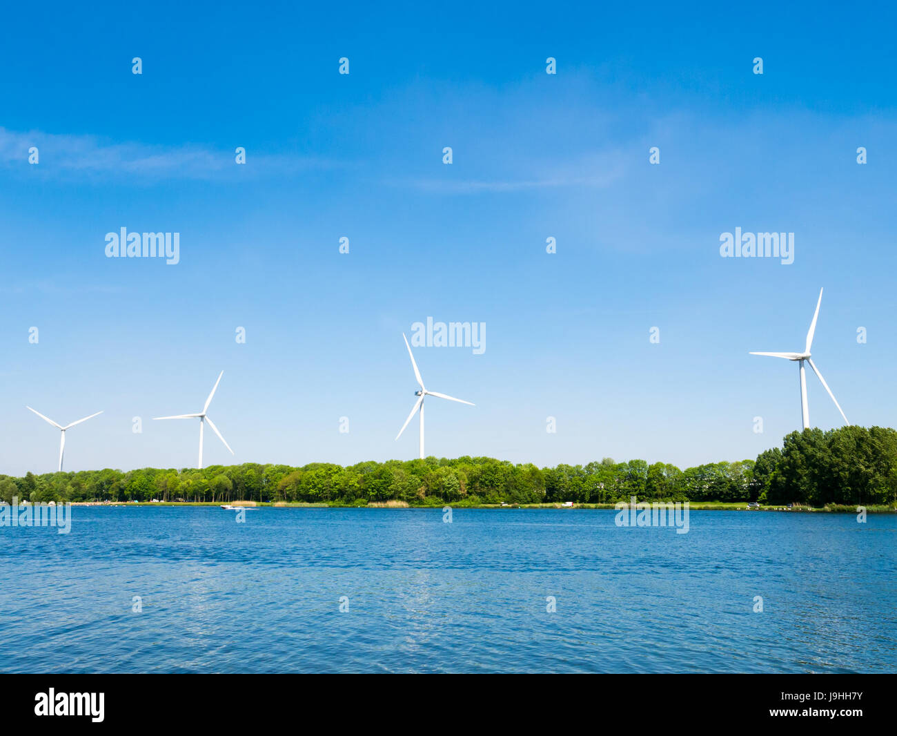 Row of four wind turbines and trees at Lake Brielse Meer near Brielle ...
