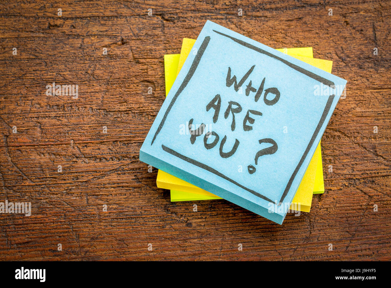 Who are you question - handwriting on a sticky note against rustic wood ...