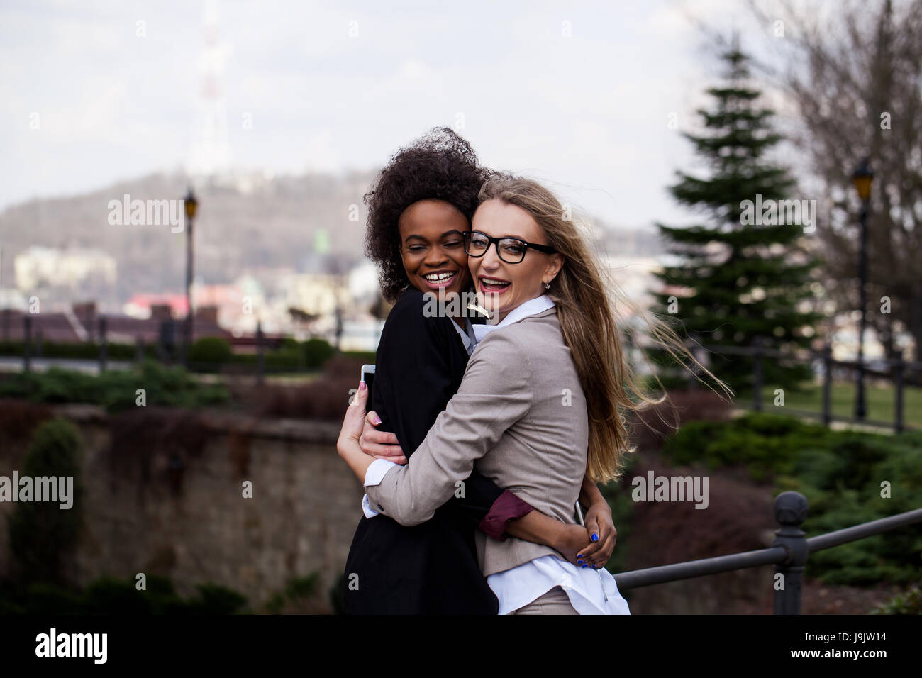 Two happy women hugging. Women wearing business clothes. One woman is ...