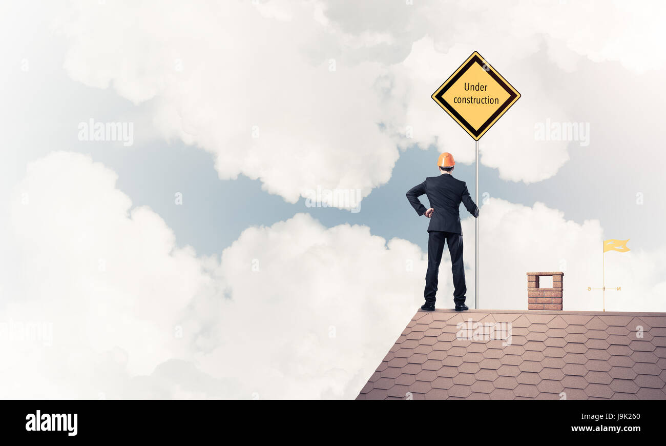 Young businessman on house brick roof holding yellow signboard Stock ...