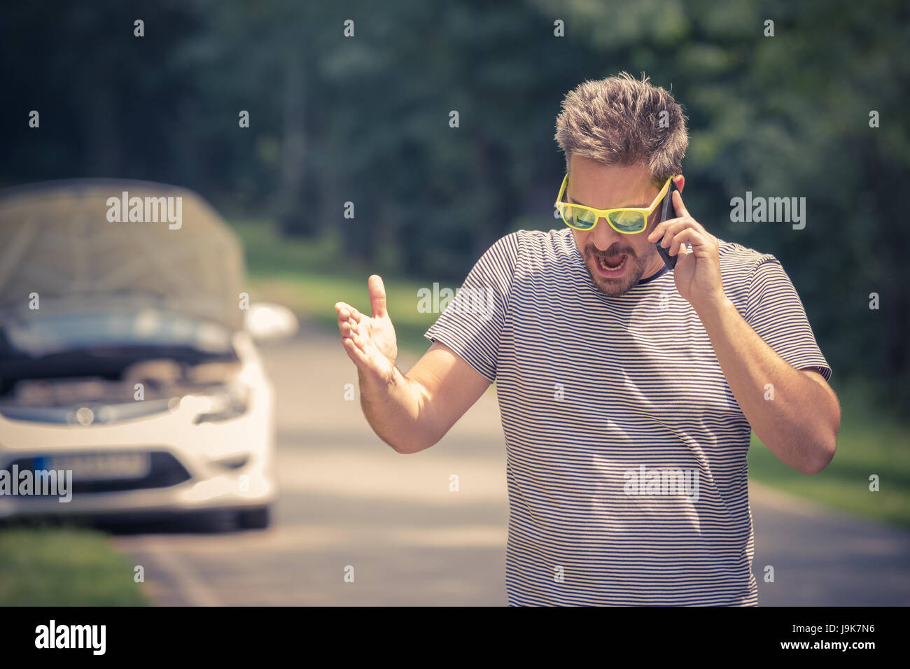 Young modern man making calling road assistance service by using ...