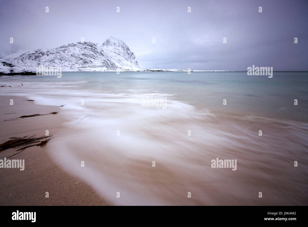 Waves of the icy sea on the beach in the background the snowy peaks ...