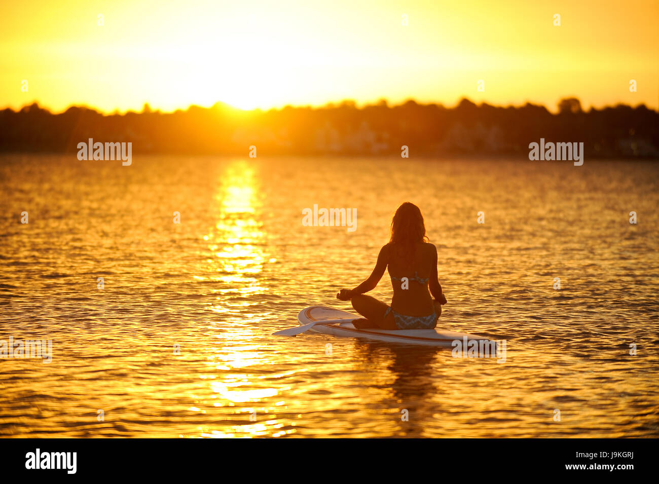 young woman doing yoga on a surfboard Stock Photo - Alamy