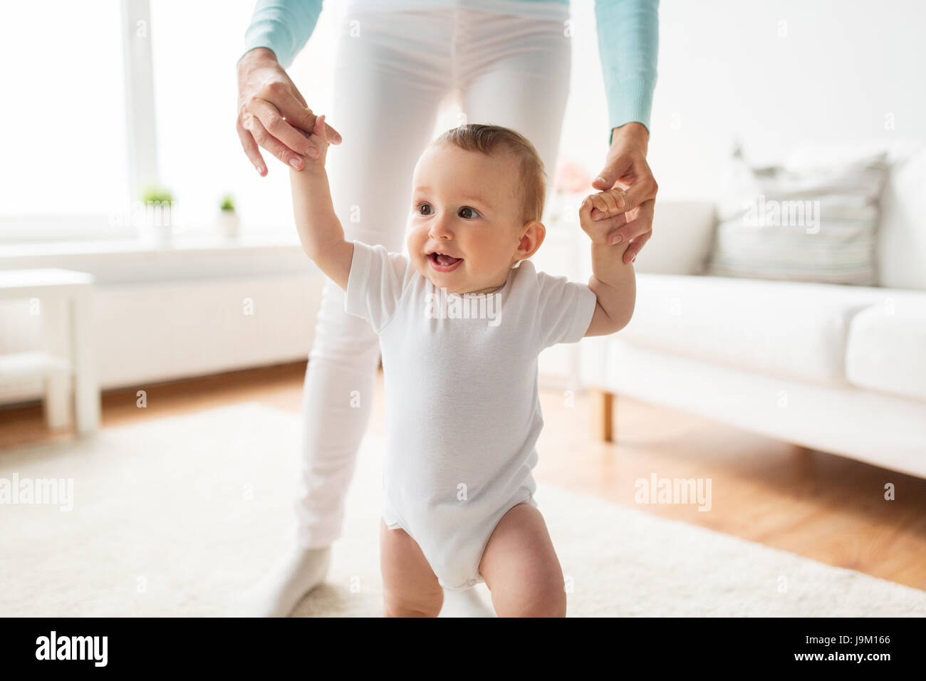 happy baby learning to walk with mother help Stock Photo - Alamy