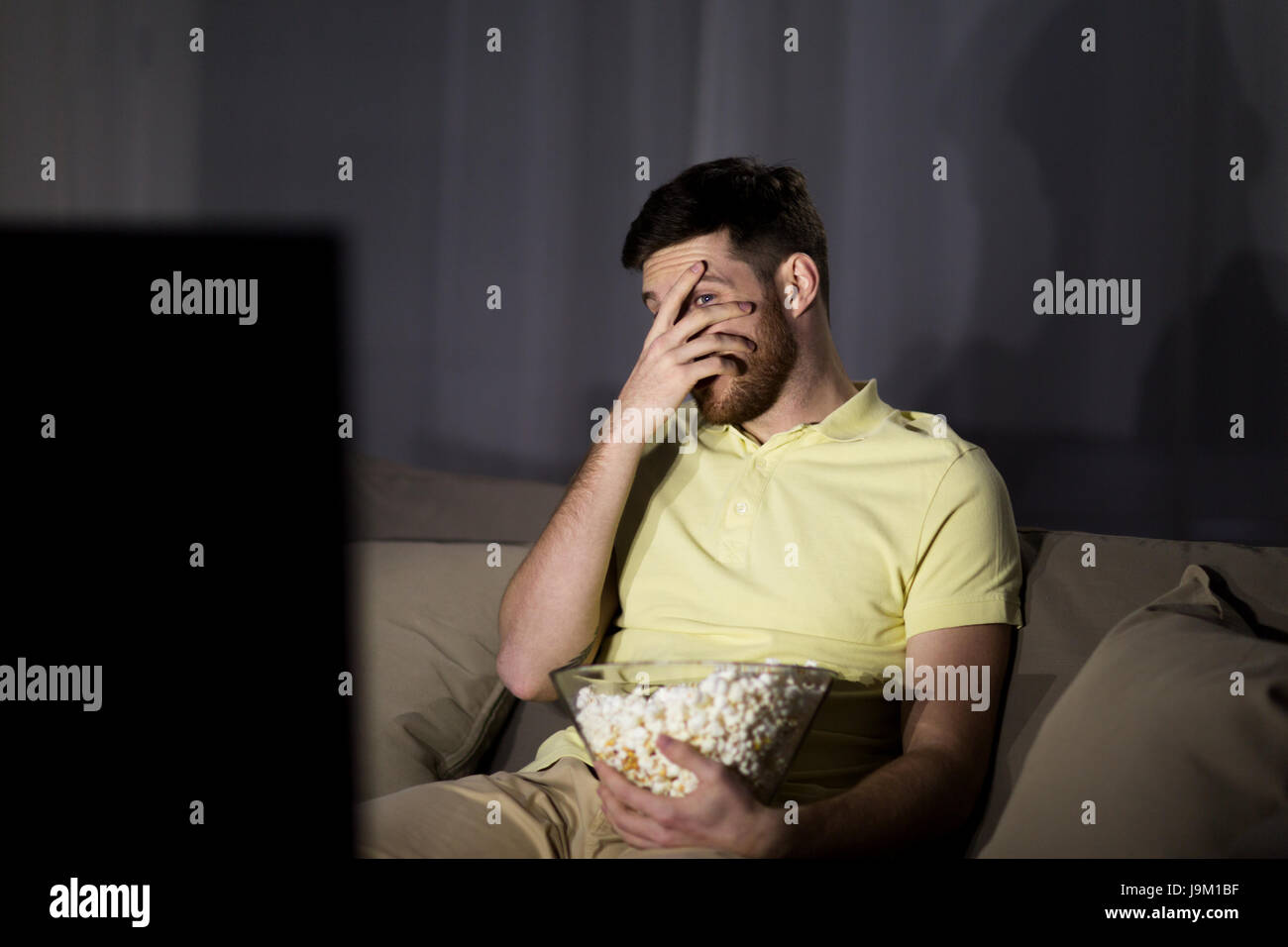scared man watching tv and eating popcorn at night Stock Photo - Alamy