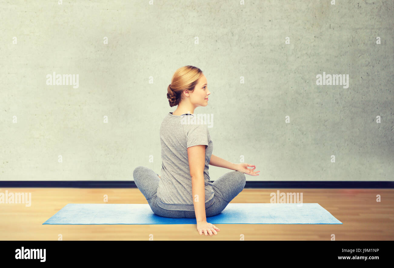 woman making yoga in twist pose on mat Stock Photo - Alamy