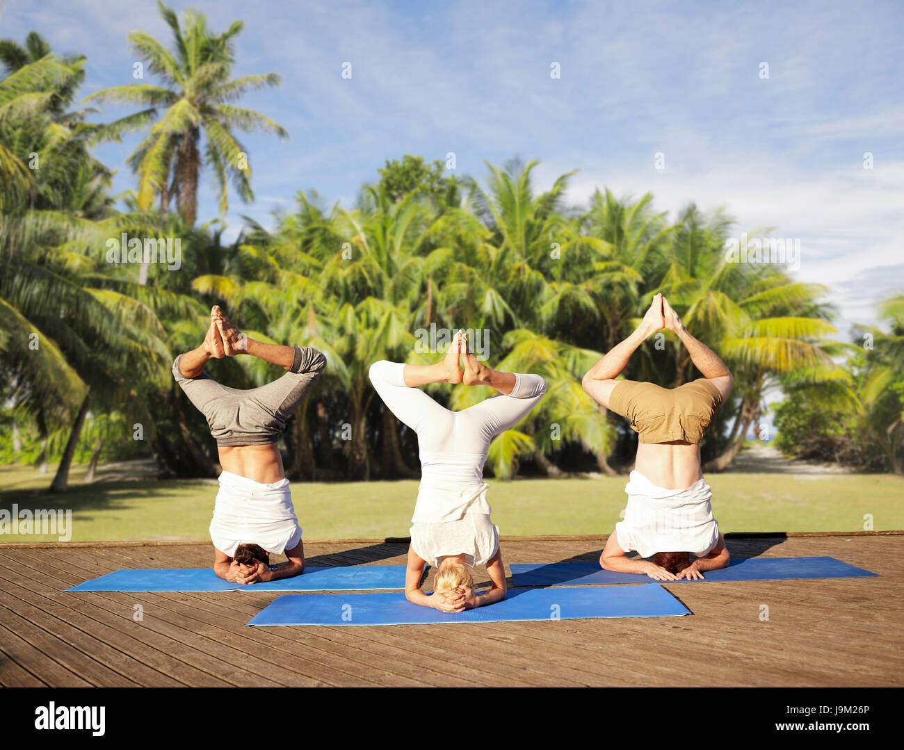 people making yoga headstand on mat outdoors Stock Photo - Alamy