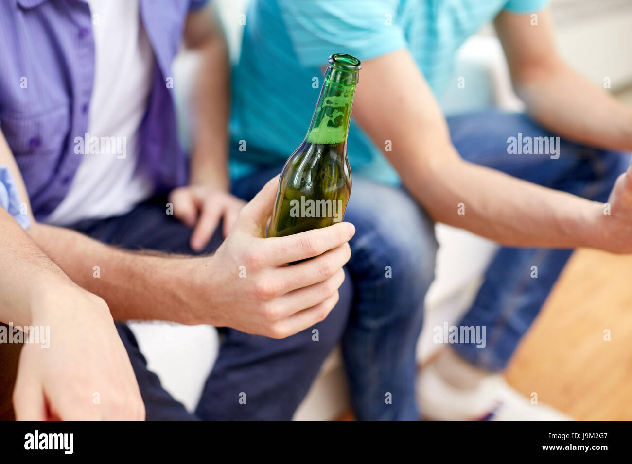 men with beer bottles sitting on sofa at home Stock Photo - Alamy