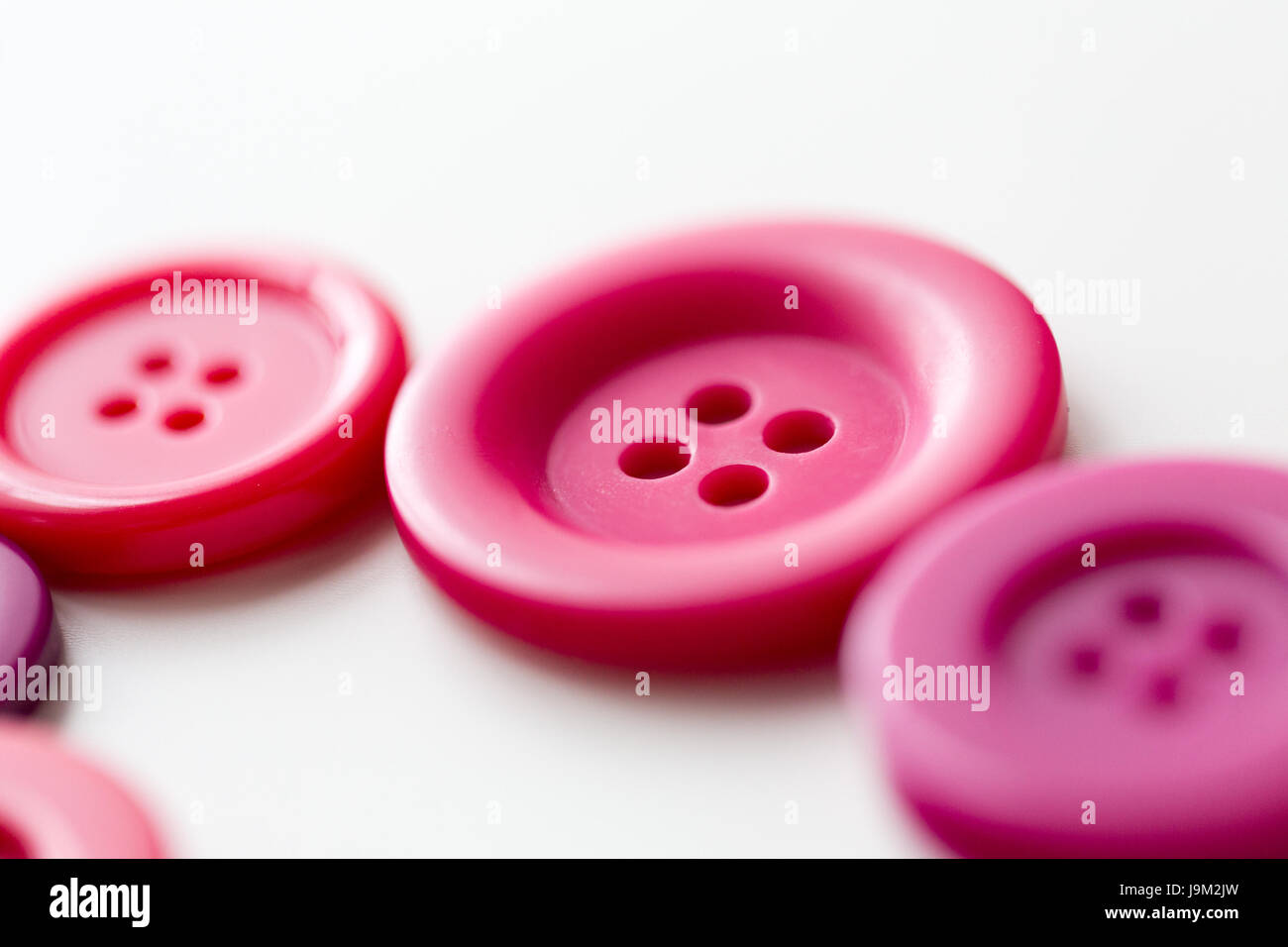 red and pink sewing buttons on white background Stock Photo - Alamy