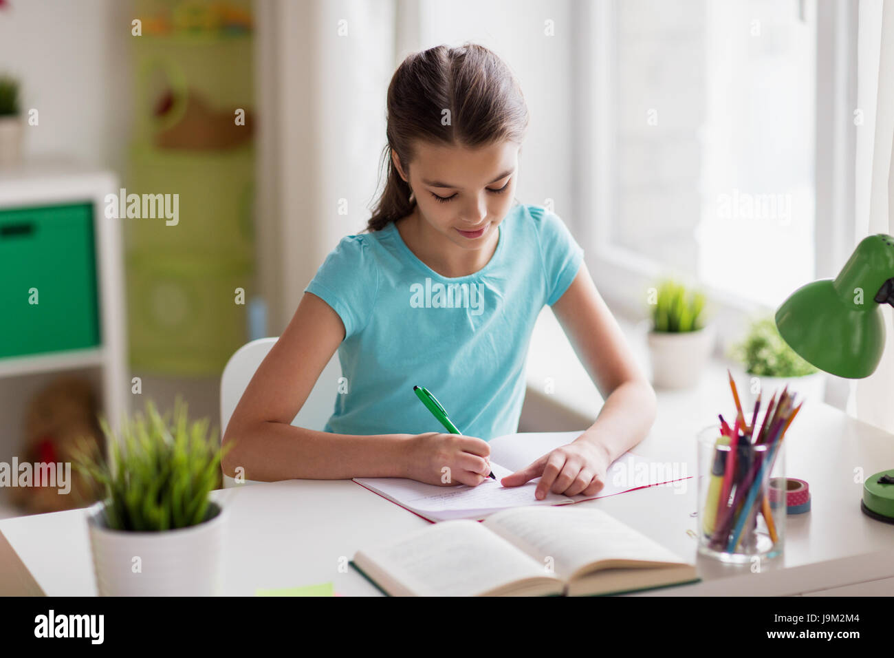 happy girl with book writing to notebook at home Stock Photo - Alamy