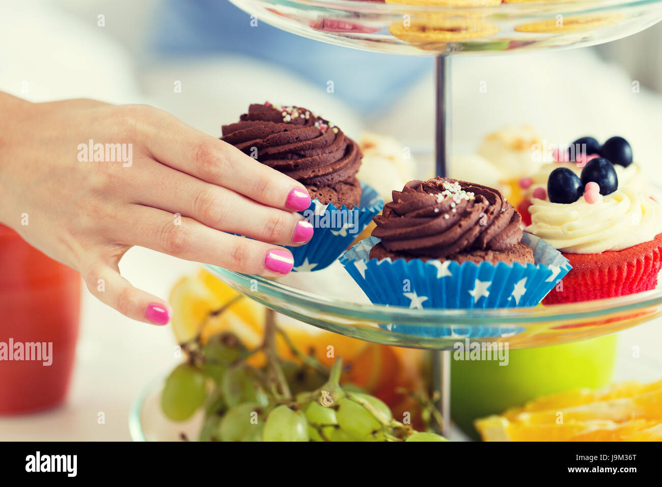 close up of hand taking cupcake from cake stand Stock Photo - Alamy