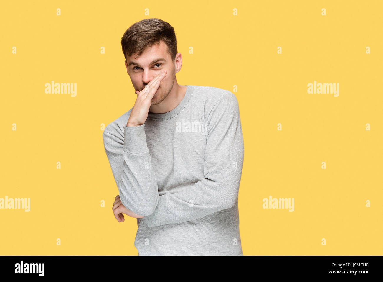 The young serious man looking cautiously and Speaking secret Stock ...