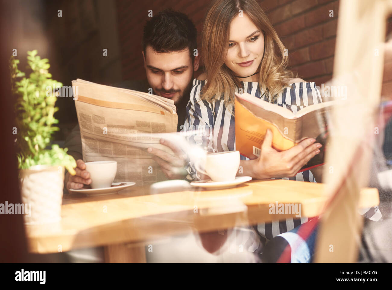 Young couple over reading in cafe Stock Photo - Alamy