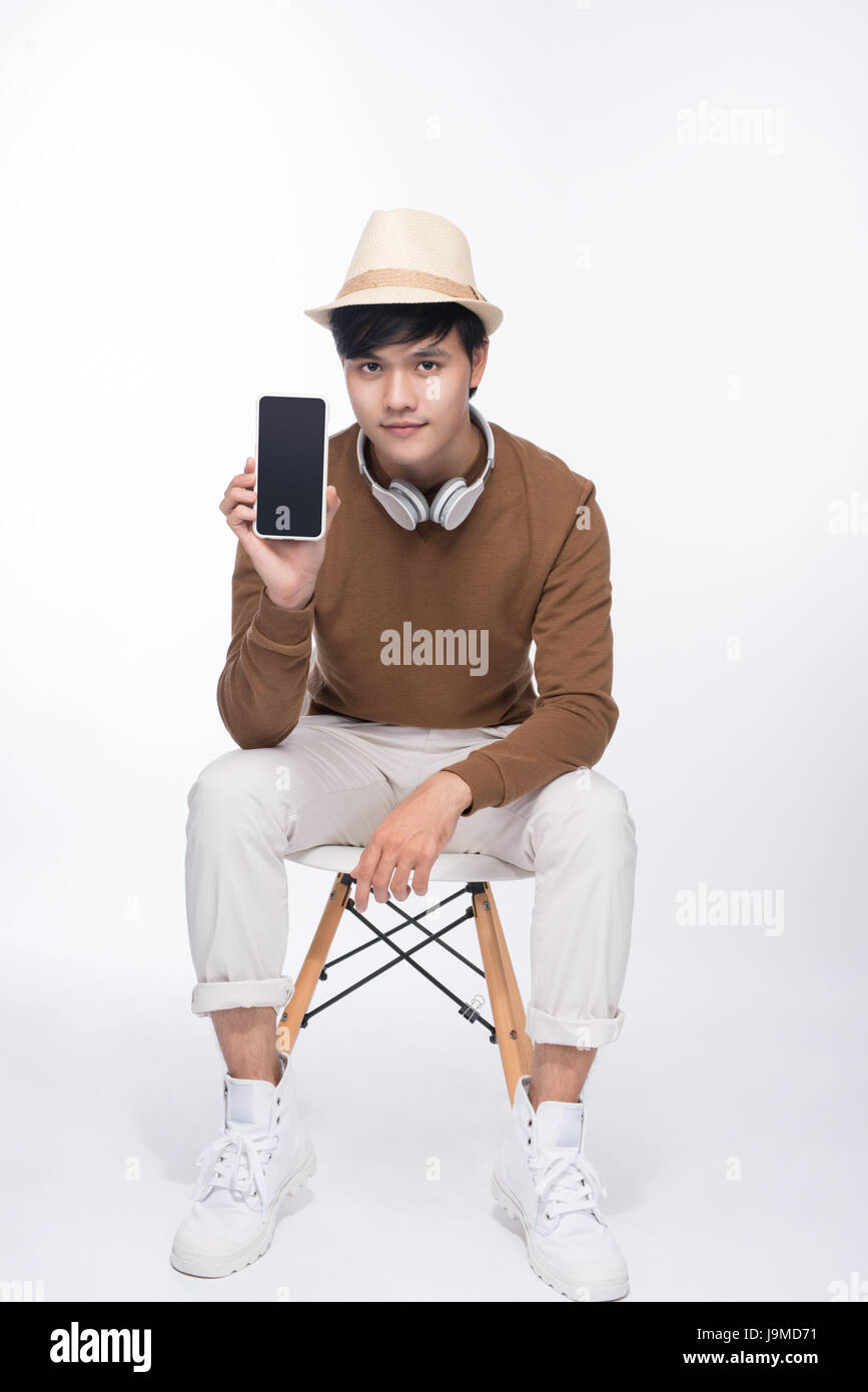 Smart casual asian man seated on chair, showing smartphone screen in ...