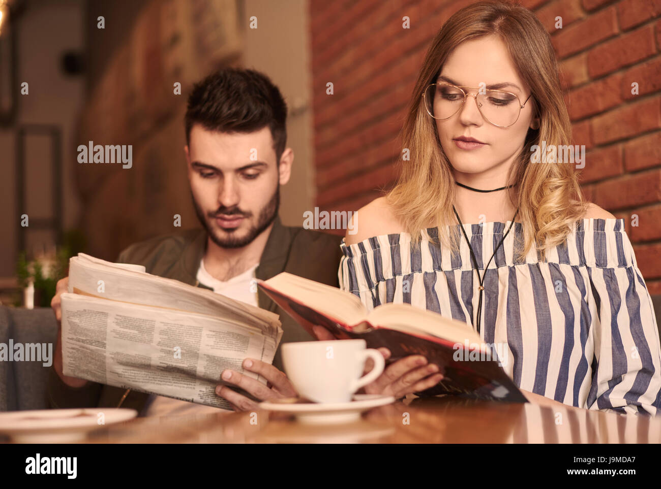 Couple over reading paper and book Stock Photo - Alamy