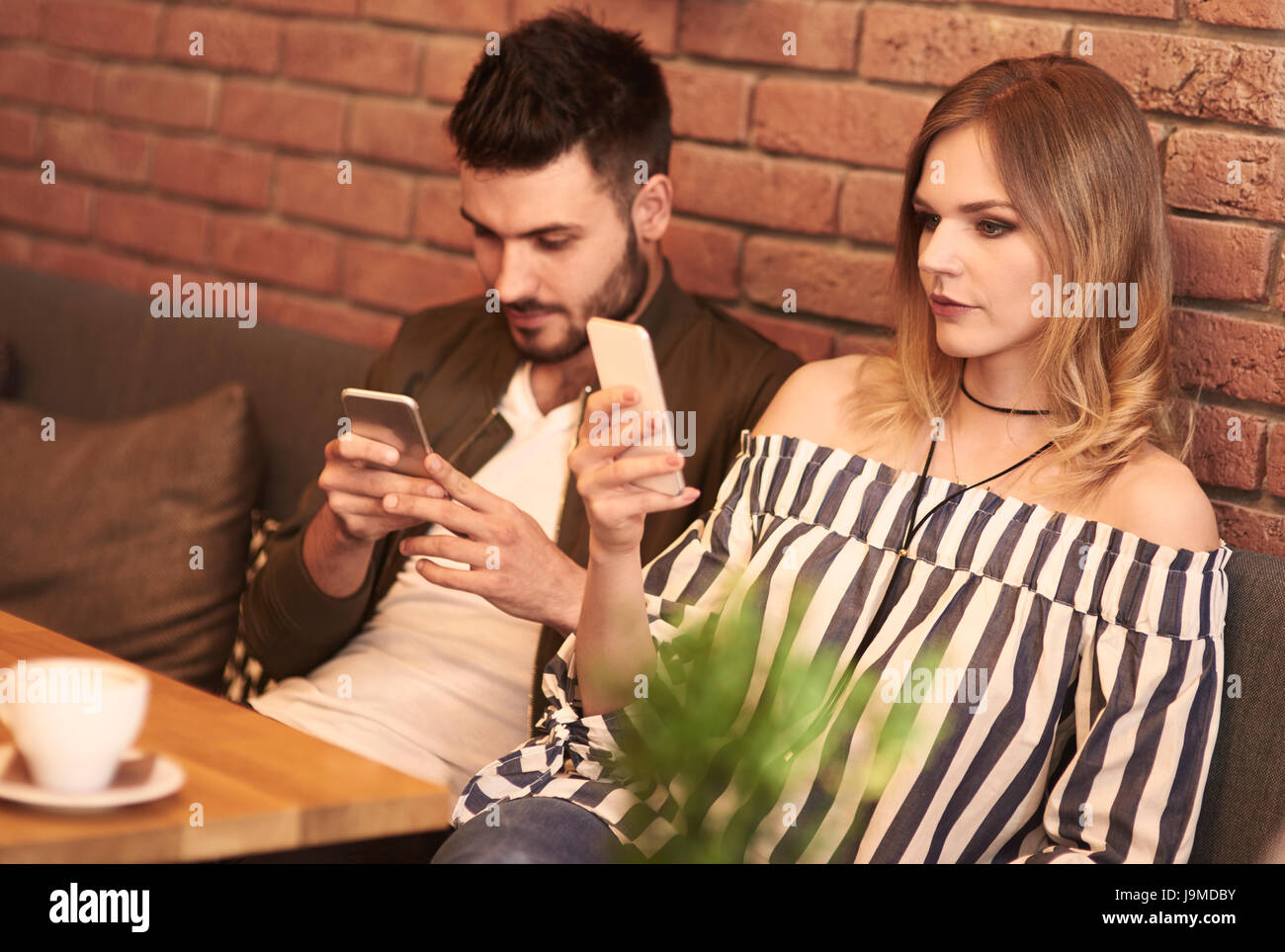 Young man with friend using cell phones Stock Photo - Alamy