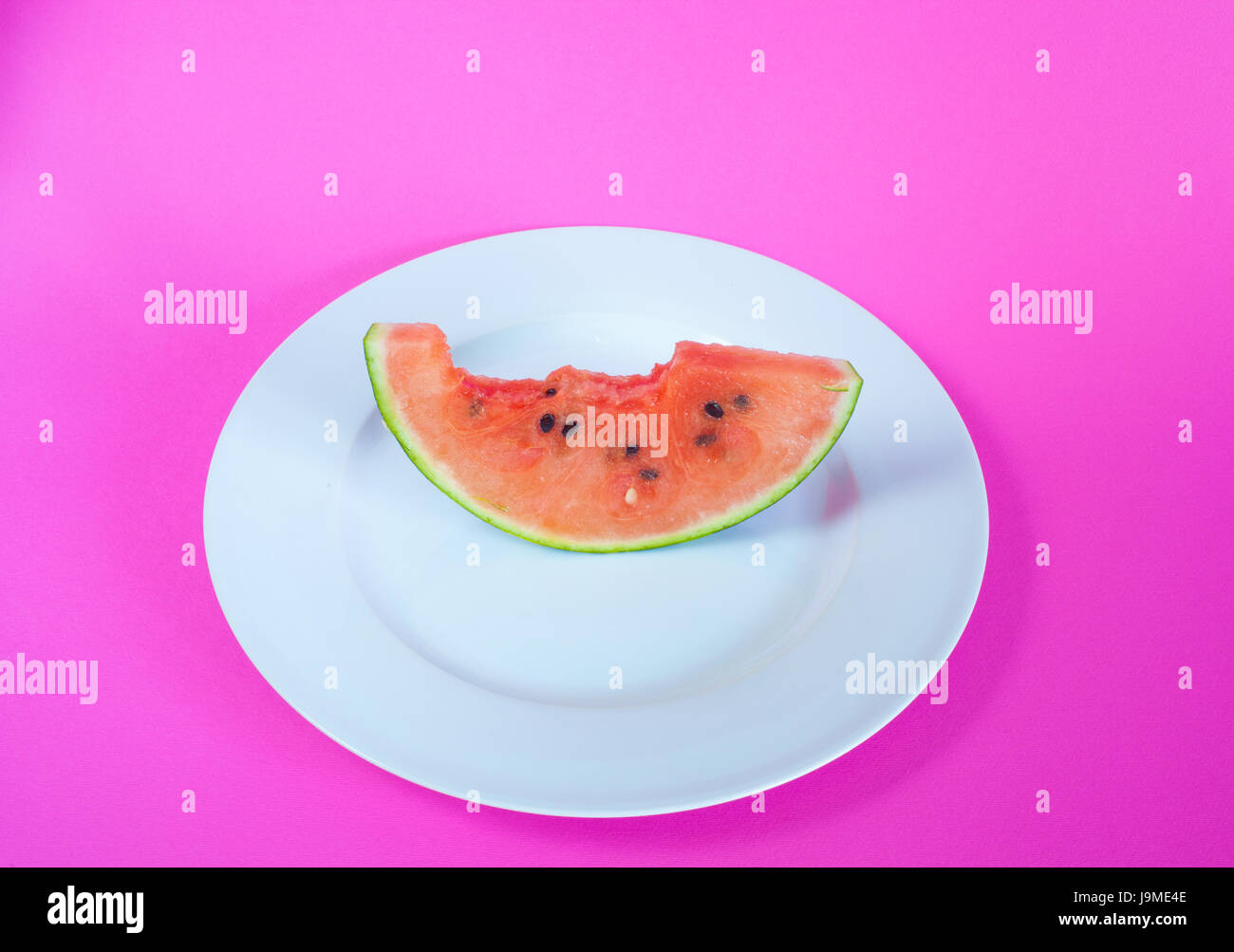 bitten watermelon slice on a white dish with purple background Stock ...