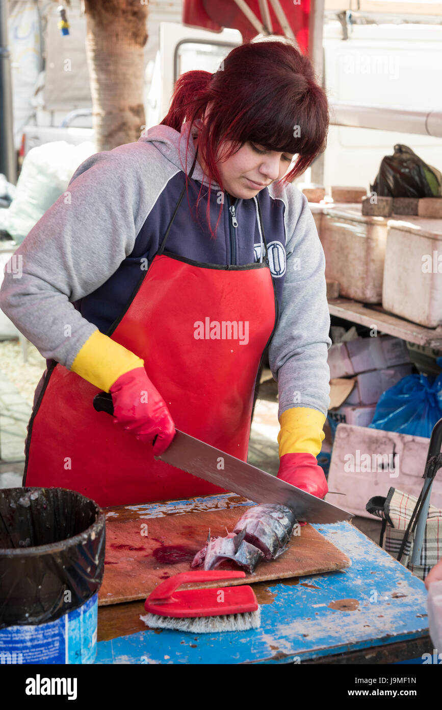 A fishmonger cutting up fish on a market stall in the market at ...
