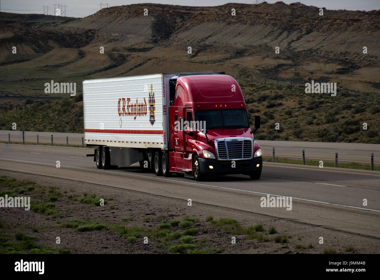 A Red Freightliner Semi-Truck pulls a white "C.R. England" trailer ...